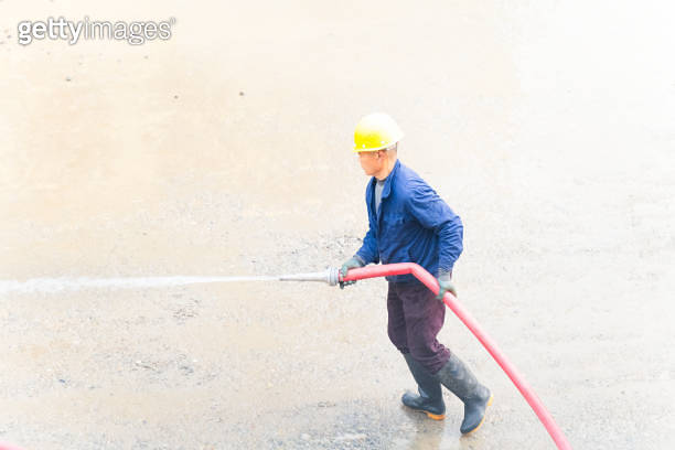 Man using water hose to clean the ground 이미지 (2098326089) - 게티이미지뱅크