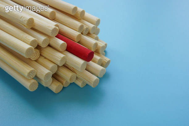 Wooden sticks and one red one as a symbol of uniqueness and difference ...