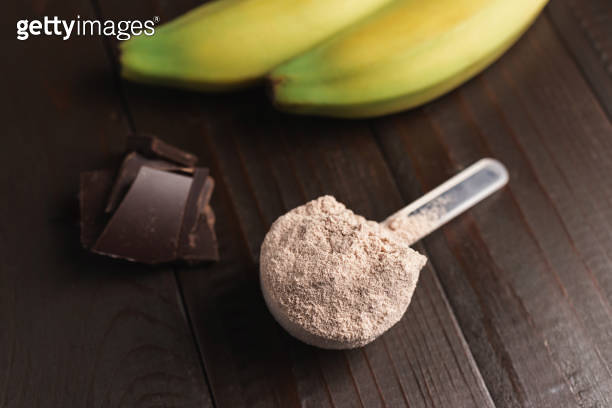 Plastic measuring spoon with whey protein powder, chocolate cubes and ...