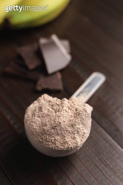 Plastic measuring spoon with whey protein powder, chocolate cubes and ...