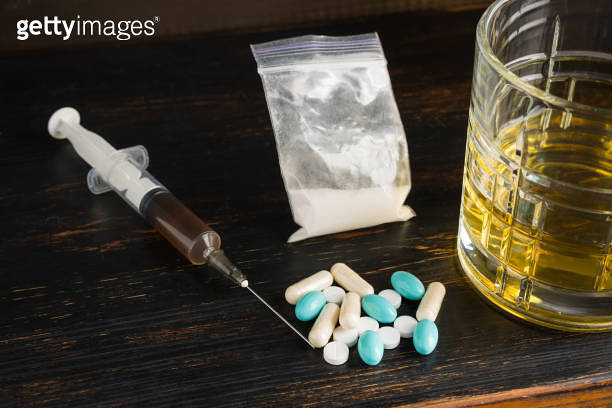 Alcohol drink in a glass, pills, syringe with drug substance, heroin ...