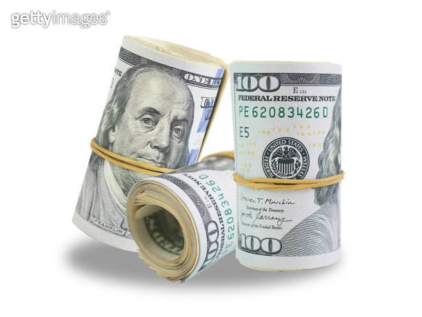 US dollar bills rolled up and secured with a rubber band on a white ...