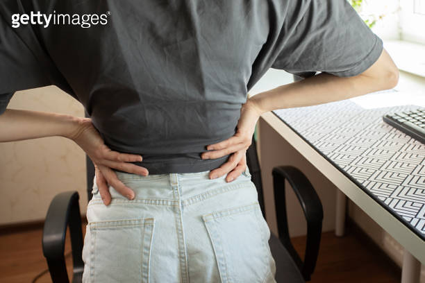 Back pain in a teenager, sedentary lifestyle, student hunched over desk ...