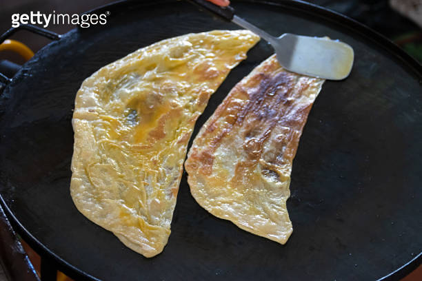 Cooking roti, a type of flatbread. The roti is being cooked on a large ...