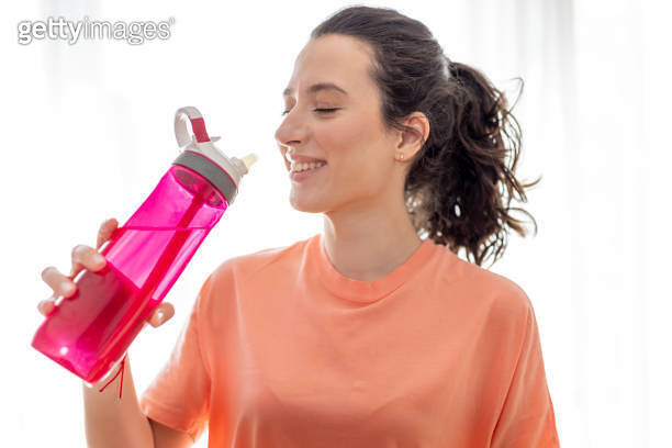 Young woman drinking water from bottle after the training. After ...