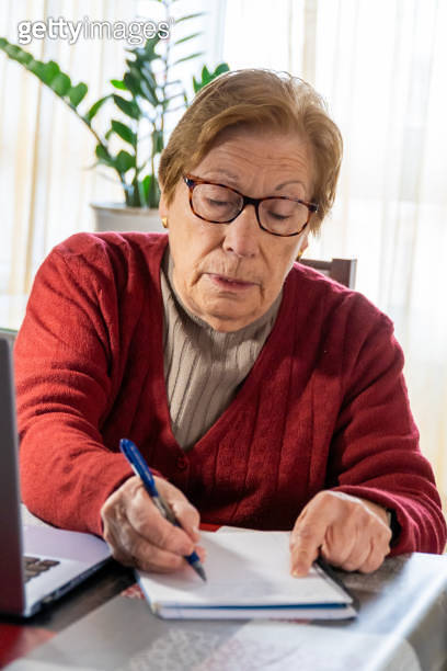Older woman writes in a notebook domestic life concept. (1919277529 ...