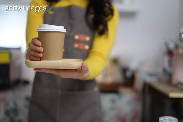 Young barista or waitress holds a coffee cup and serves it to a ... Young barista or waitress holds a coffee cup and serves it to a ...
