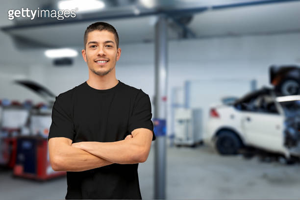 Car mechanic poses with his arms crossed in front of his auto repair ...