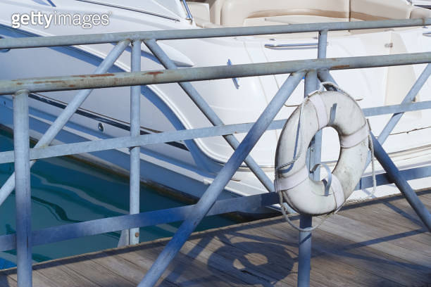 Safety ring life preserver attached to a metal railing on a dock with a ...
