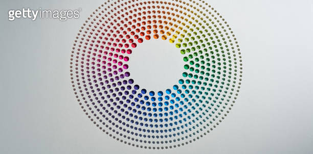 Circular perforated paper art with vibrant rainbow colors arranged in a ...