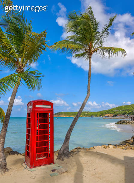 Traditional English red telephone booth on a the beach of Dickenson Bay ...