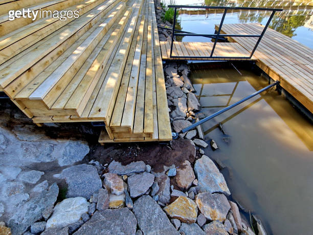 a floating jetty for mooring ships is fixed with metal rods on hinges ...