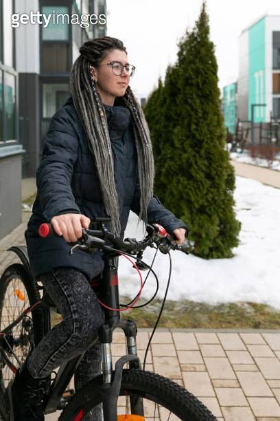 Urban pretty woman with dreadlock hairstyle rides a bicycle 이미지 ...