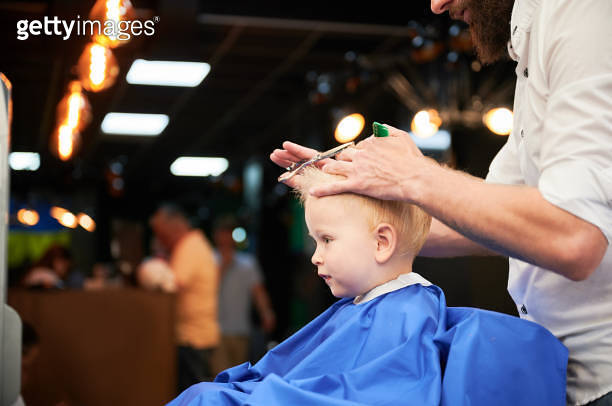 Behind shoulder view of male barber cutting little boy's hair. 이미지 ...