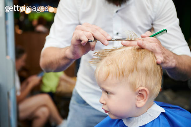 Behind shoulder view of male barber cutting little boy's hair. 이미지 ...