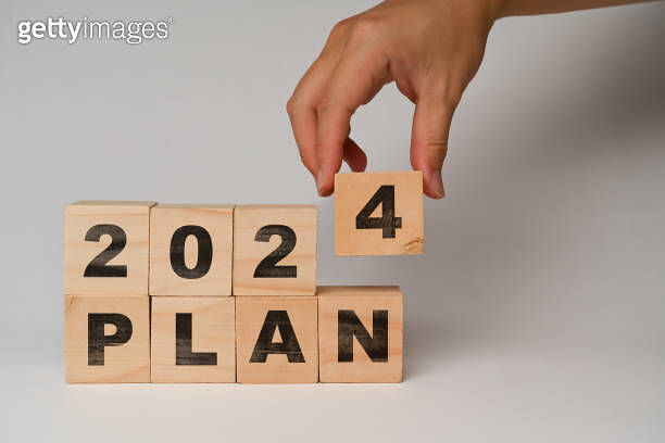 Hand placing wooden cube blocks with 2024 PLAN text on white background ...