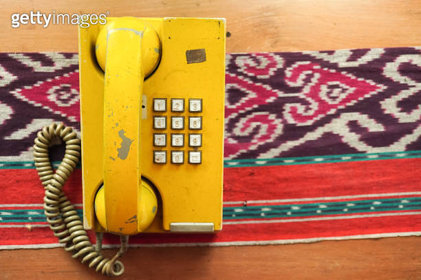Yellow old fashioned landline telephone that uses the number buttons ...