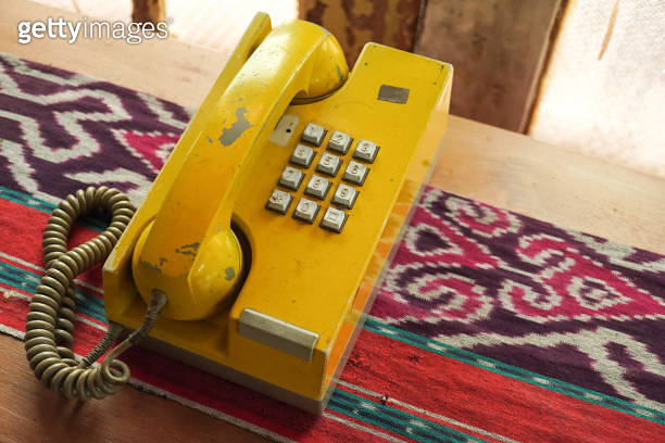Yellow old fashioned landline telephone that uses the number buttons ...
