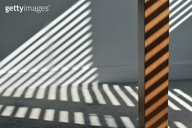Shadow from venetian blind falling across a wall and table leg. Surreal ...