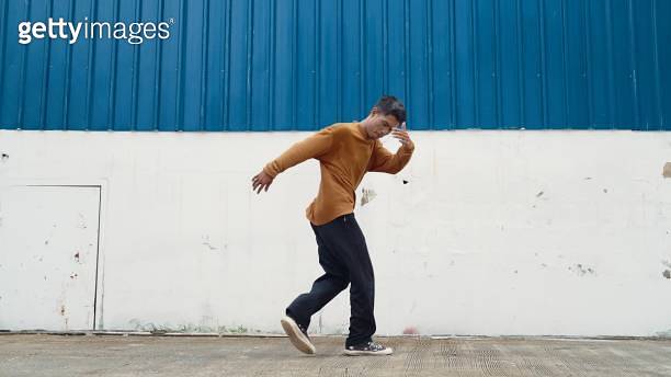 Hispanic man stretch arms and dance street dancing in front of wall ...