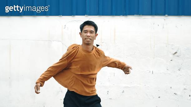 Hispanic man stretch arms and dance street dancing in front of wall ...