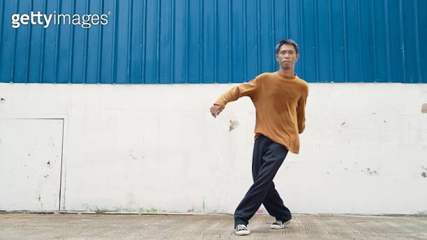Hispanic man stretch arms and dance street dancing in front of wall ...