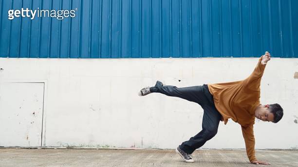 Hispanic man stretch arms and dance street dancing in front of wall ...