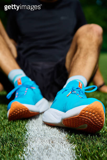 Athlete Wearing Bright Blue Running Shoes on Green Grass Track During ...
