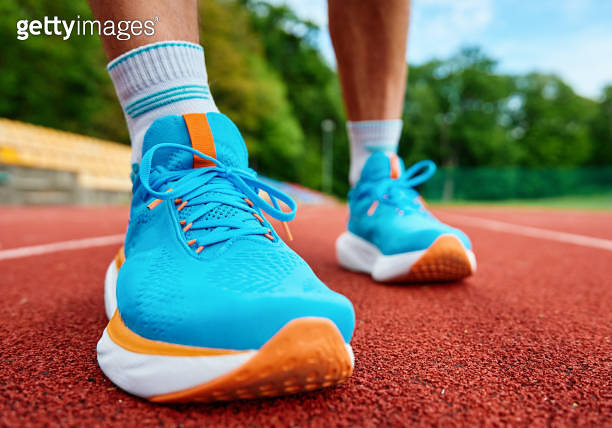 Athlete Wearing Bright Blue Running Shoes on Red Stadium Track During ...