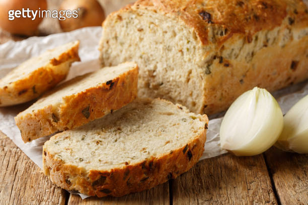 Freshly baked onion bread sliced loaf close-up on parchment. Horizontal ...