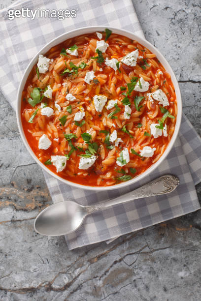 Greek pasta kritharaki or orzo with tomato sauce, feta, onion and herbs ...