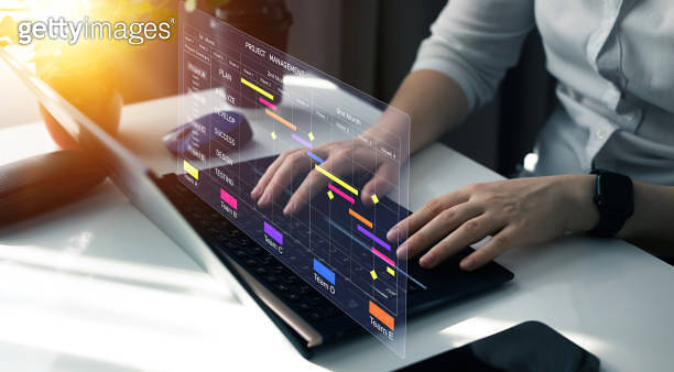 Project manager working on laptop and updating tasks and milestones ...