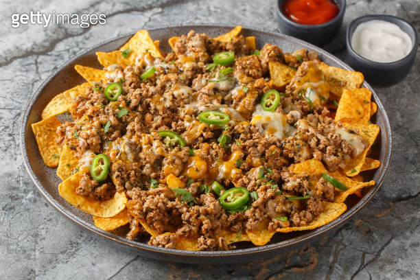 Traditional nachos with ground beef, cheddar cheese and jalapeno pepper ...