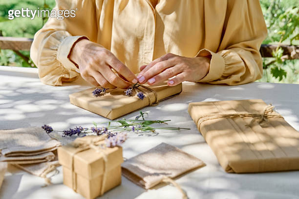 Woman making hand made gift package with craft recycled paper and dried ...