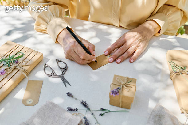 Woman making hand made gift package with craft recycled paper and dried ...