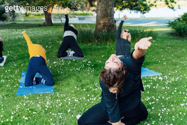 Female yoga class in park. Group of diverse women doing stretching pose ...
