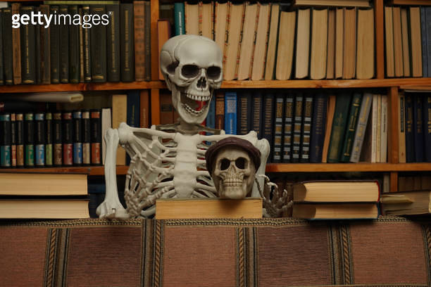 Human skeleton and skull in cap. Bookshelves with books. (2162545329 ...