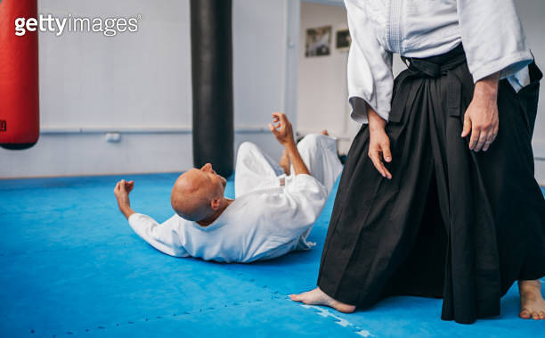 Two men are practicing Aikido in dojo wearing traditional white Kimono ...