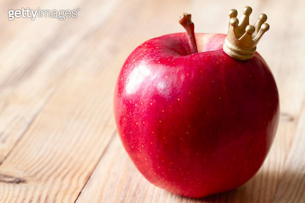Apple with crown on wooden background, king of fruits concept abstract ...