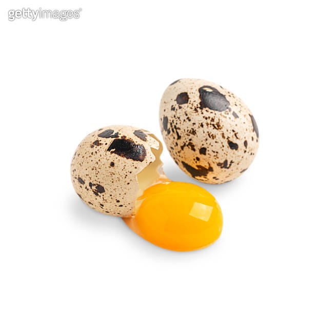Whole and broken raw spotted quail eggs with yellow yolk isolated on white used as healthy ...