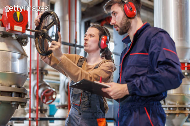Young Woman and Man Tackle Tasks at Heating Plant (1924241442) - 게티이미지뱅크