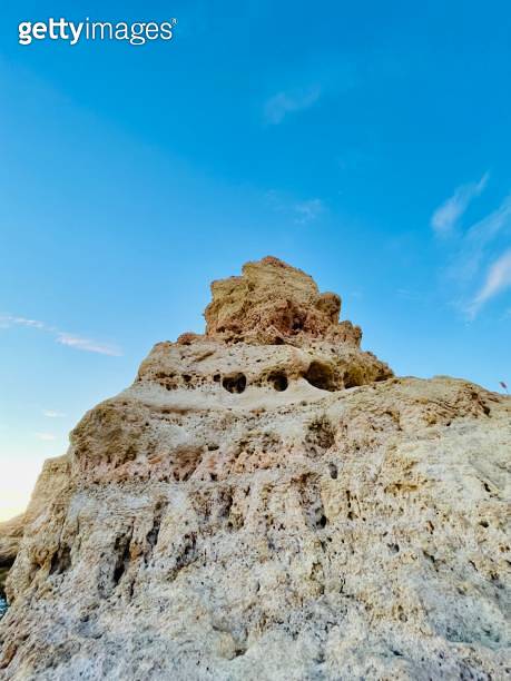 Towering limestone cliffs with lots of caves rise up from a stormy sea ...