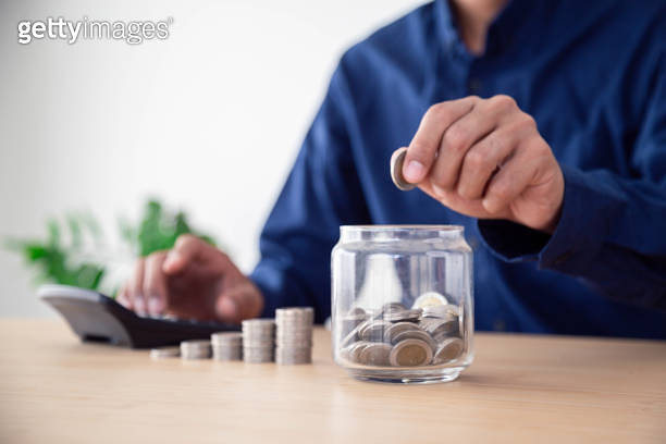 Man saving money concept. hand holding coins putting in jug glass ...
