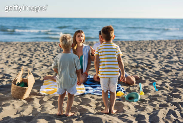 Family Relaxing on Beach with Kids Playing 이미지 (2161217832) - 게티이미지뱅크