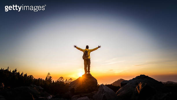 Male hiker climbing the mountain - Strong hiker with hands up standing ...