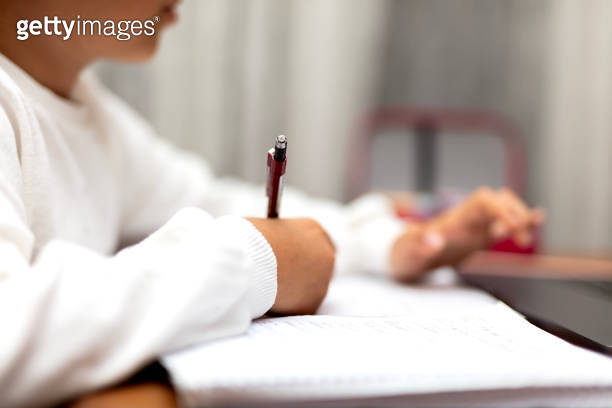 Teenage girl making notes in notepad, doing homework at table at home ...