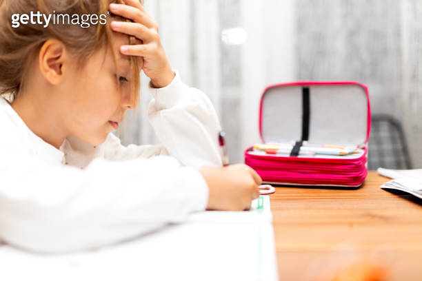 Teenage girl making notes in notepad, doing homework at table at home ...