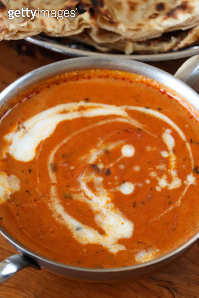 Full frame image of kadhi-style metal serving dish of butter chicken ...