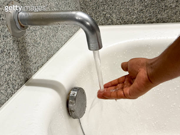 Close-up image of unrecognisable person testing water temperature of ...