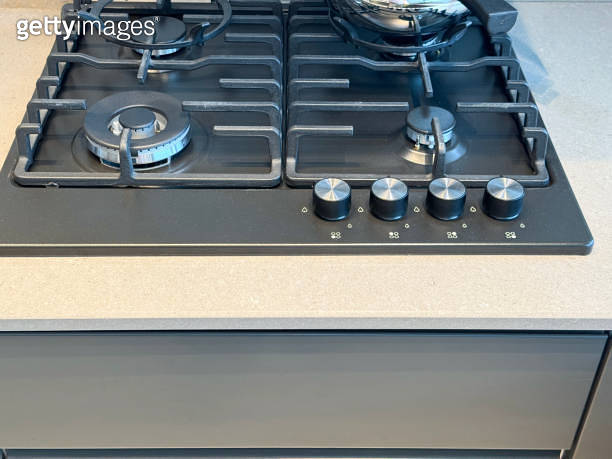 Close-up image of modern kitchen 4 burner gas hob in beige-grey quartz ...